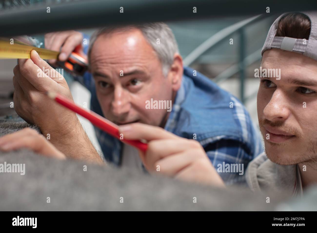 builder apprentice and senior workmen measuring wall Stock Photo - Alamy
