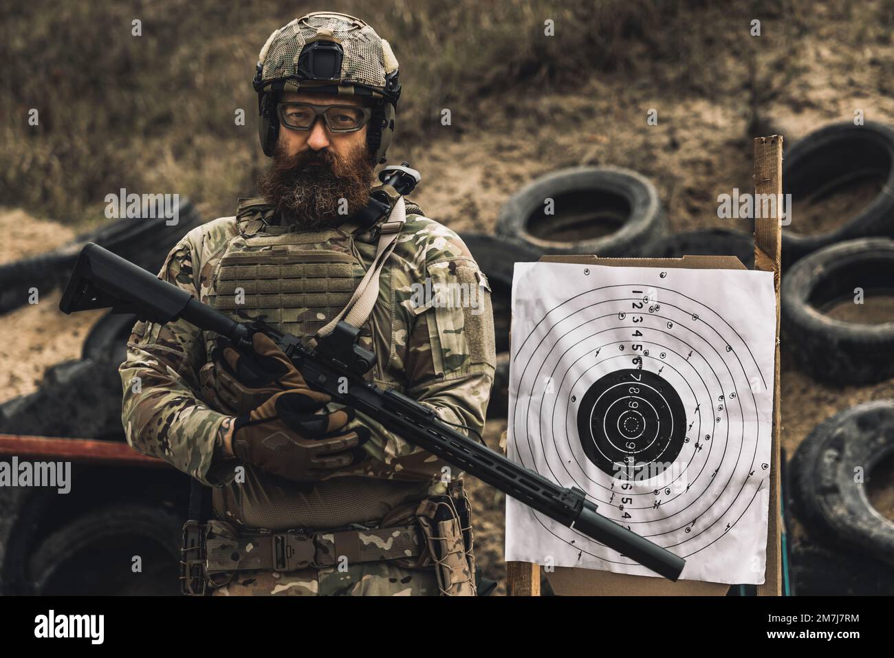 Mature soldier standing near the shooting target with rifle in hands ...