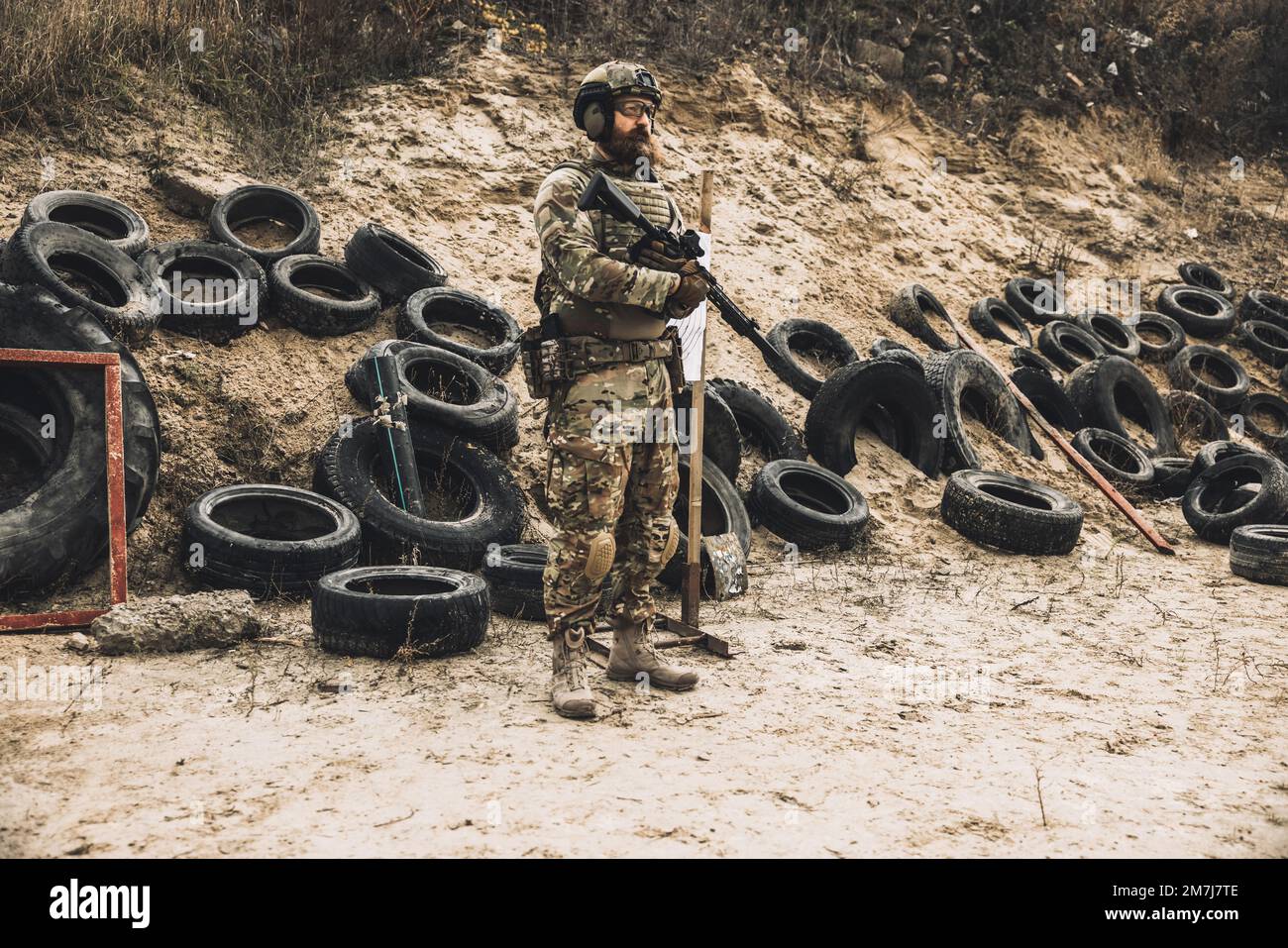 Mature soldier standing near the shooting target with rifle in hands ...