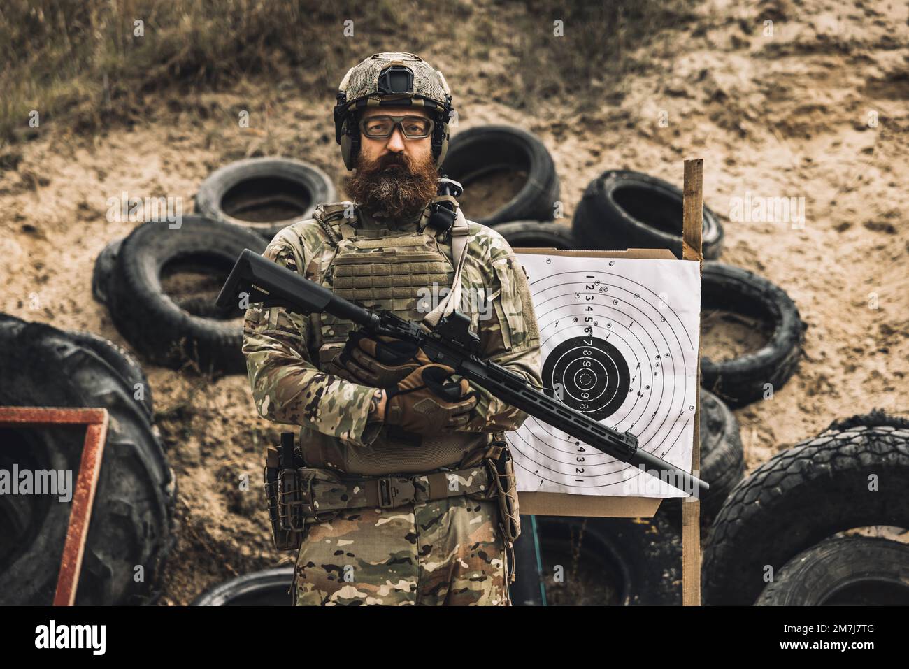 Mature soldier standing near the shooting target with rifle in hands ...