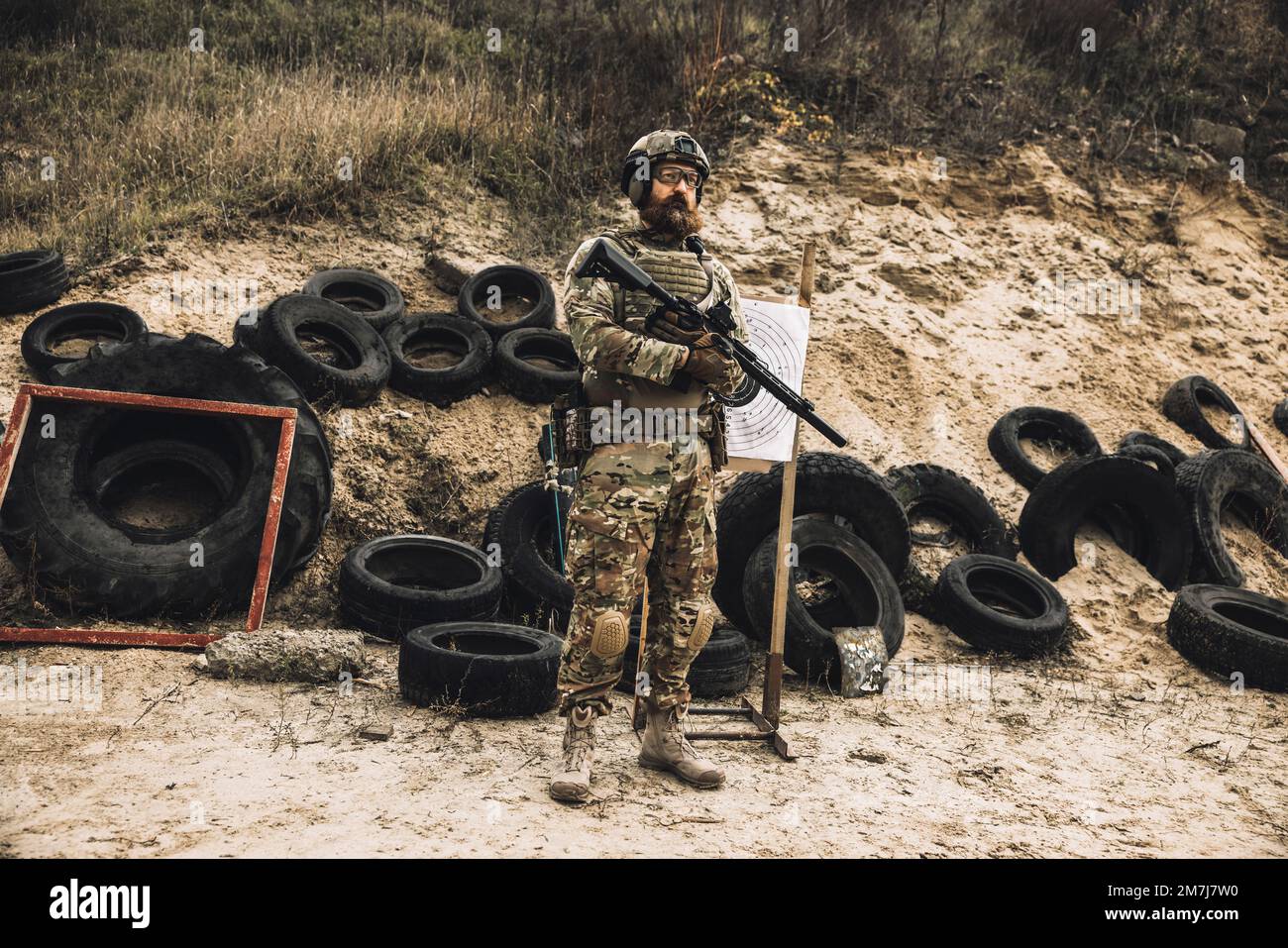 Mature soldier standing near the shooting target with rifle in hands ...