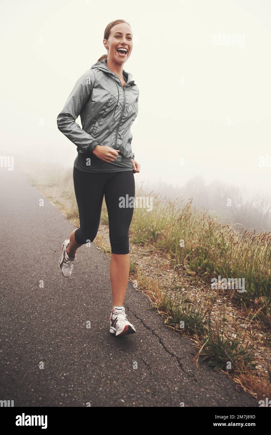 I love a run in solitude. A young woman jogging on a country road on a ...