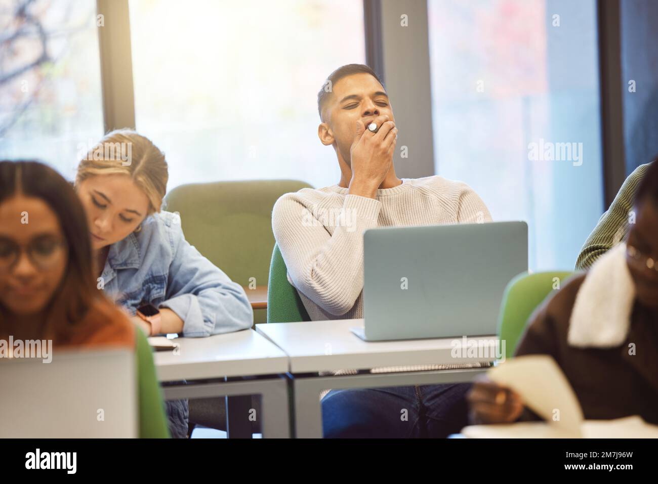 Education, man and student tired, classroom and studying for exams ...