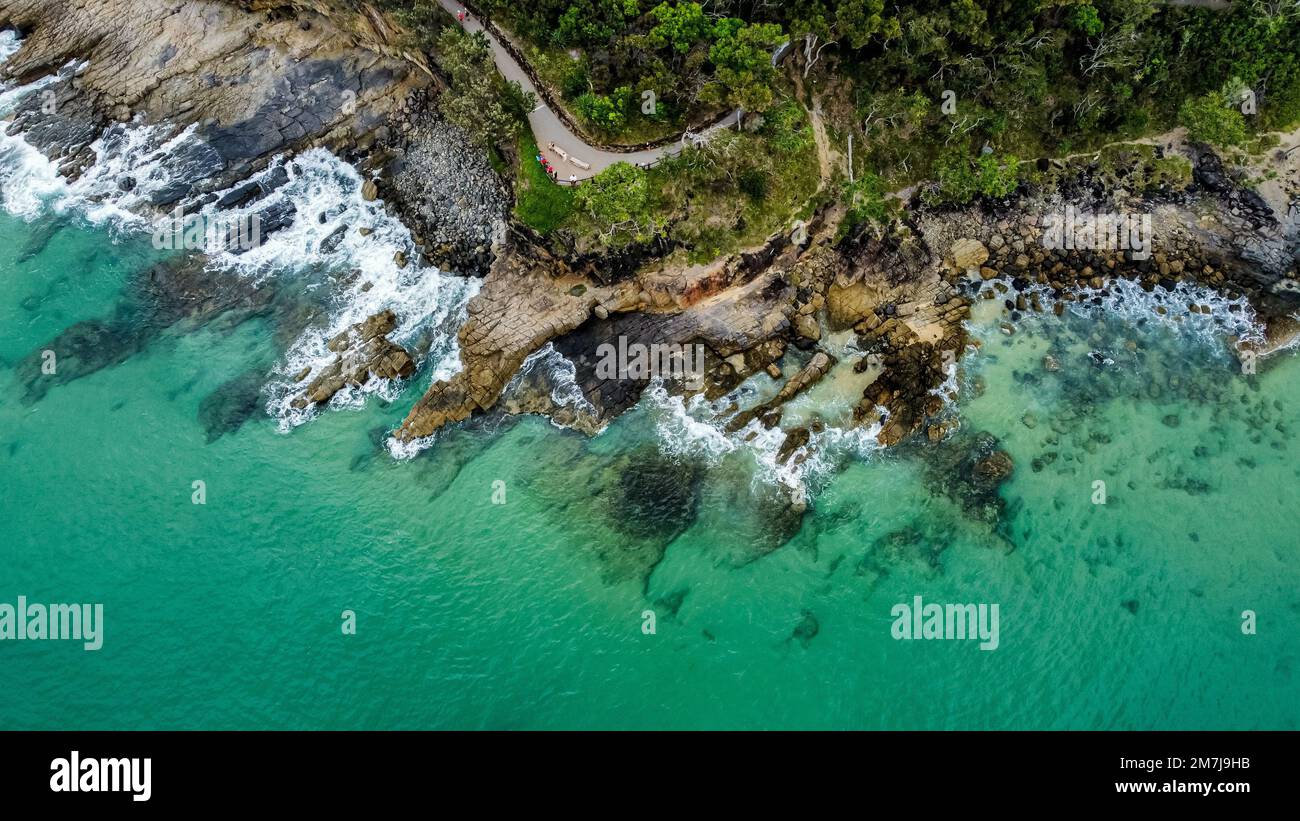 An aerial view of turquoise ocean water waves crashing on rocky island ...