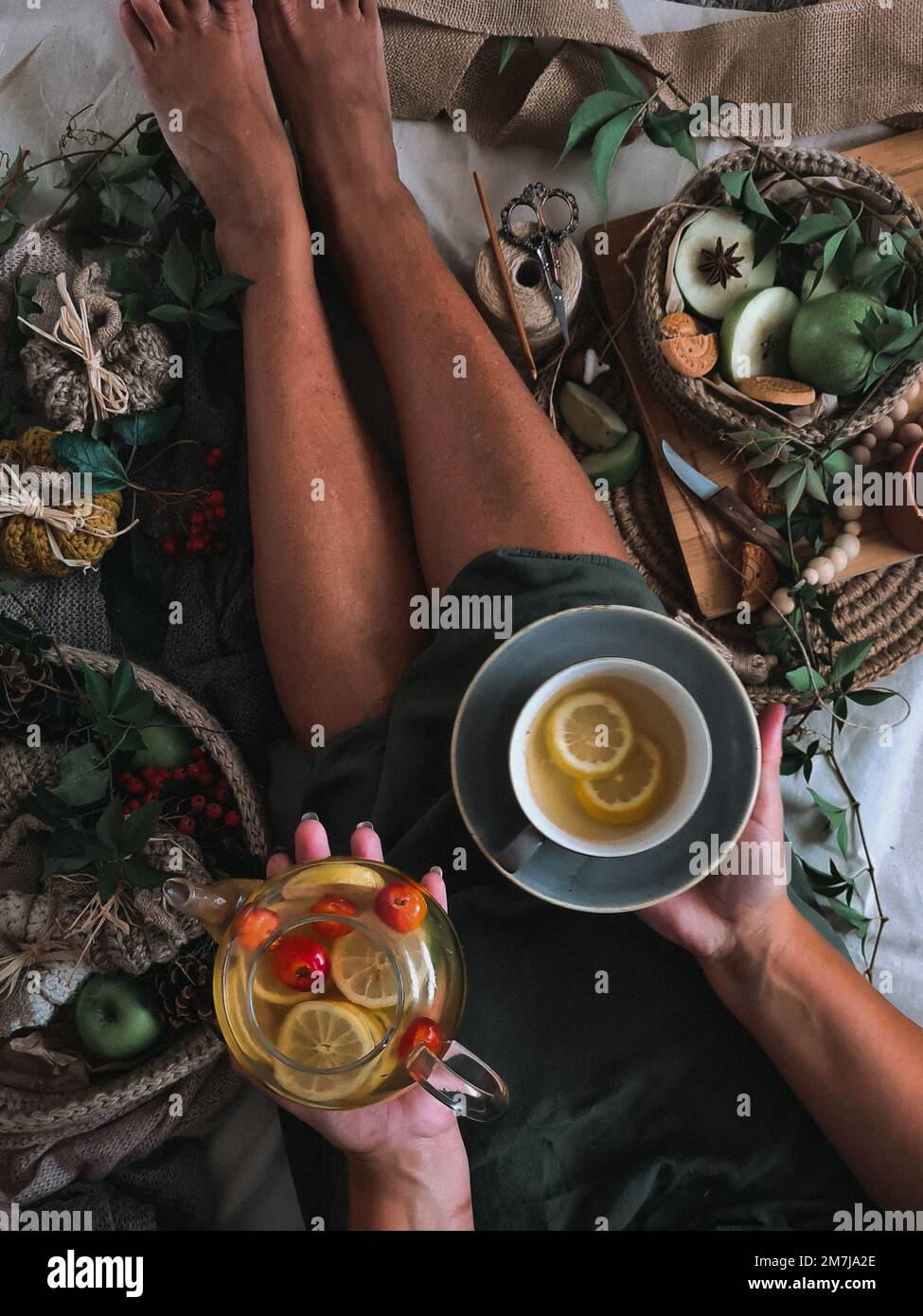 A beautiful view of female hands holding tea on her legs with fruits ...