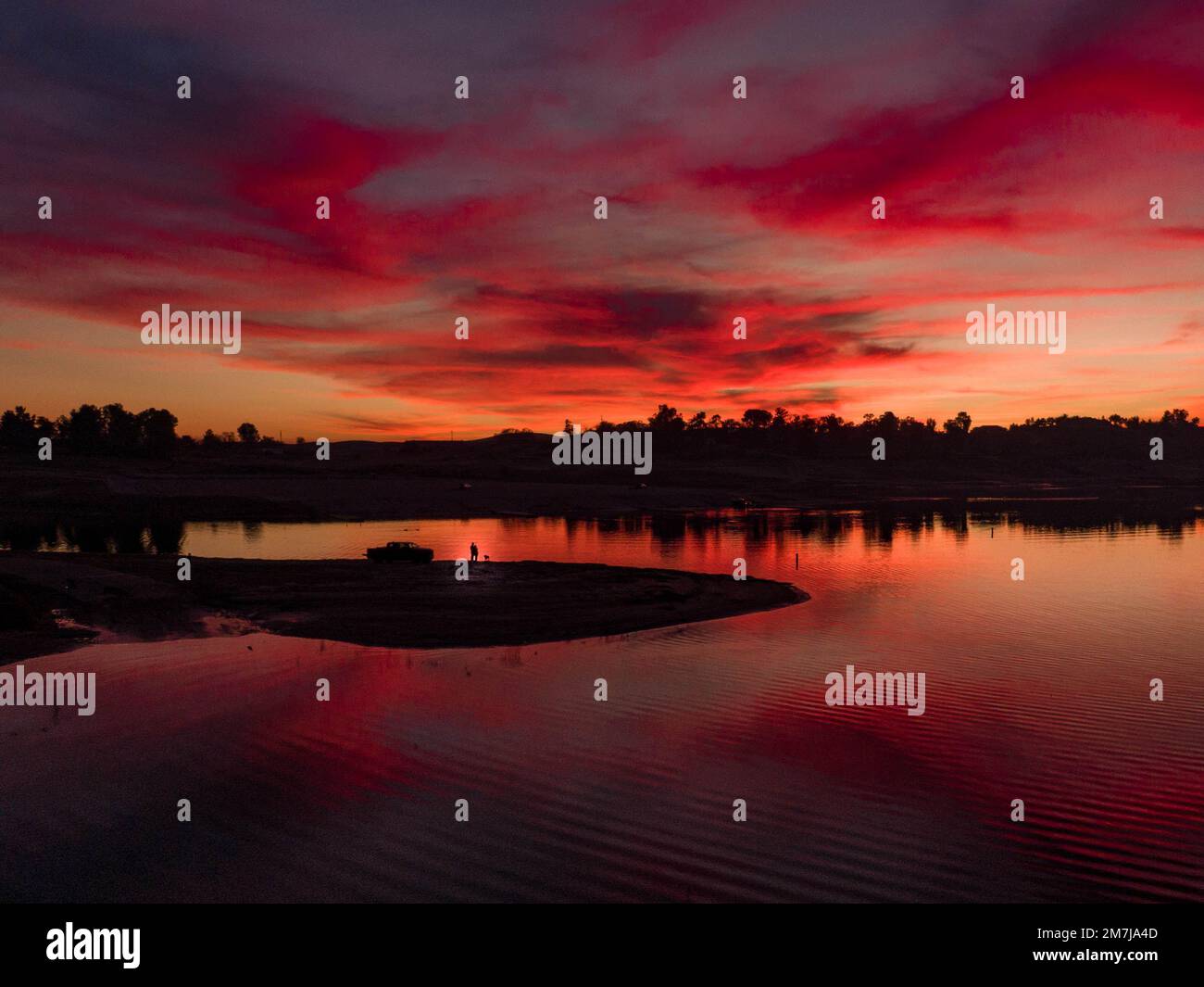 A red sunset over a lake with a small island in the middle Stock Photo ...