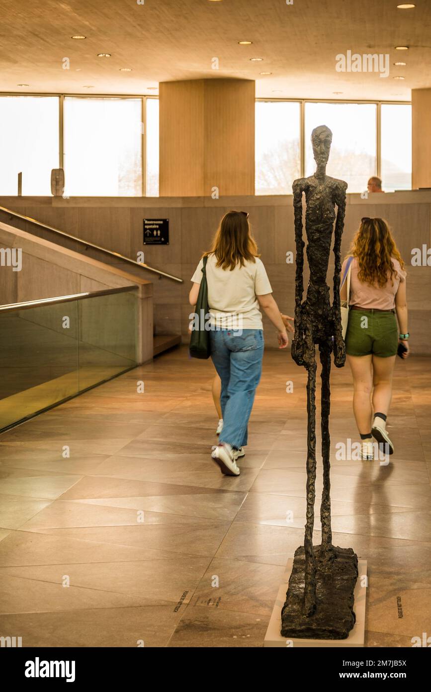 Two women walking past sculpture by Alberto Giacometti: Walking Man II ...