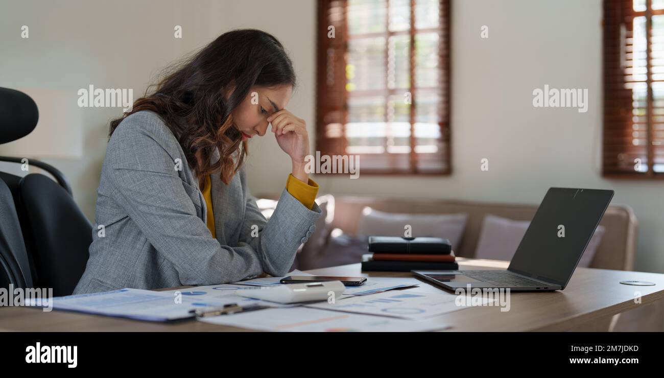 Stressed Asian business woman worry with many document on desk at ...