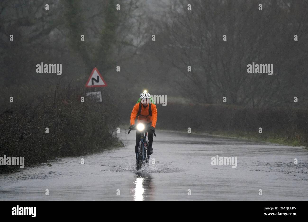 A cyclist makes their way through flood water on Kent Lane, near to ...