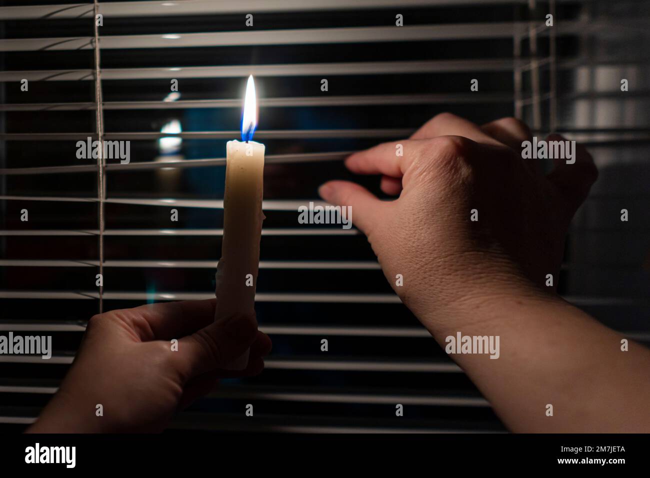 Burning candle in the hands against the background of a window with ...