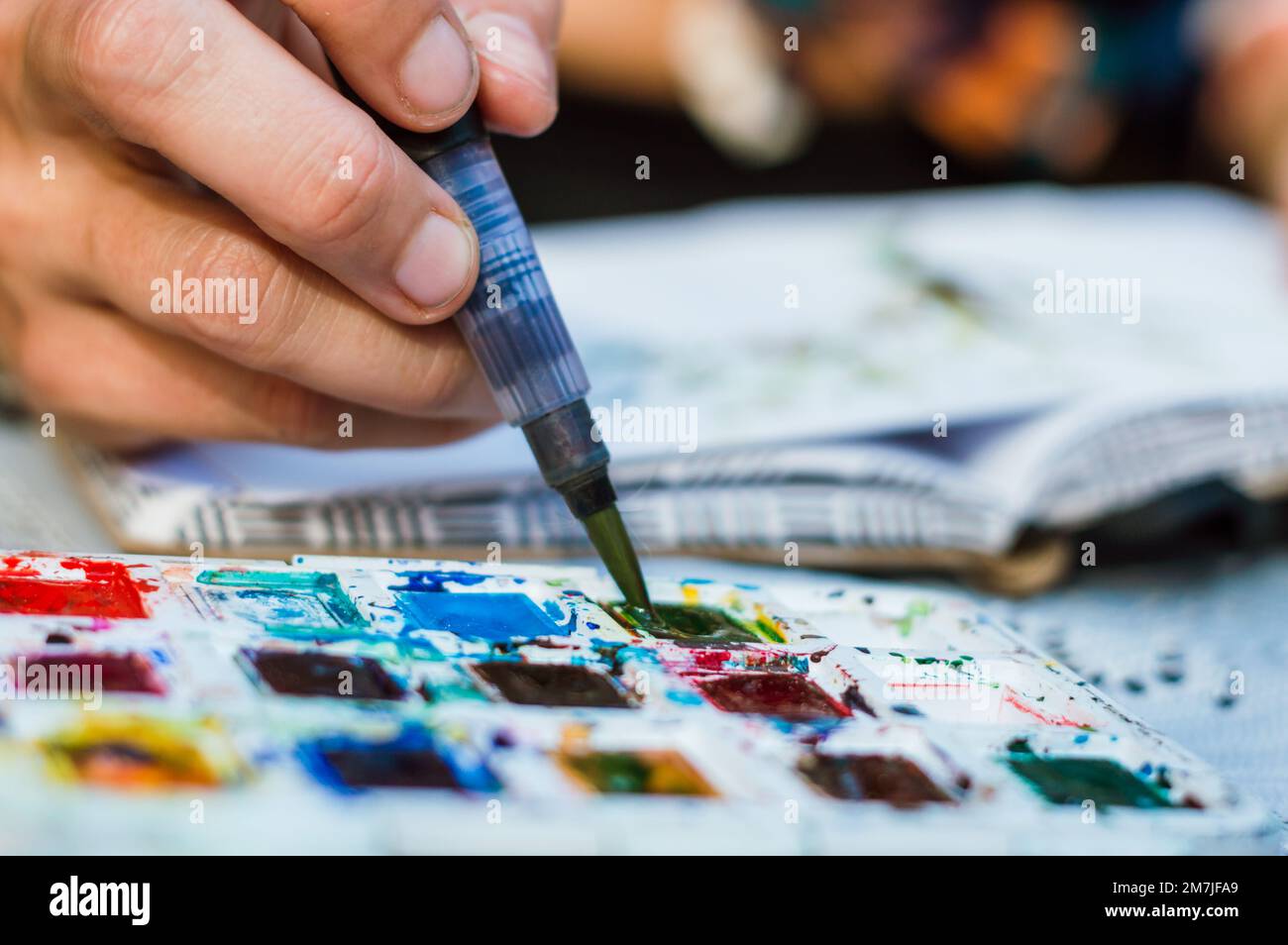 detail of female caucasian hand dipping the brush into green colored ...