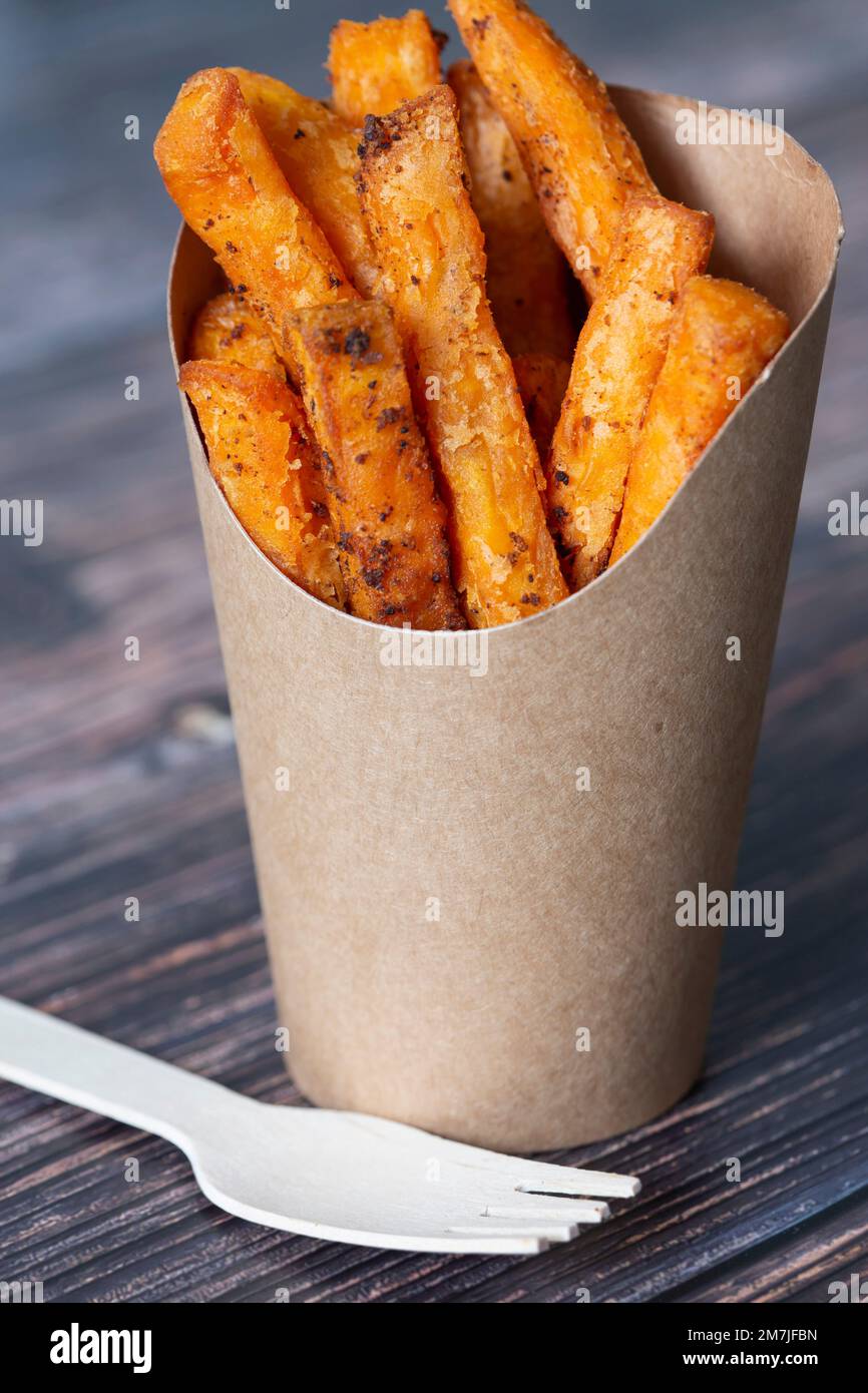 Sweet potato fries in a takeaway card container box with a wood fork ...