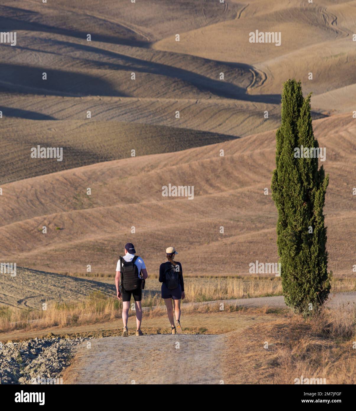 Visitors walk along path in the countryside at San Quirico d'Orcia ...