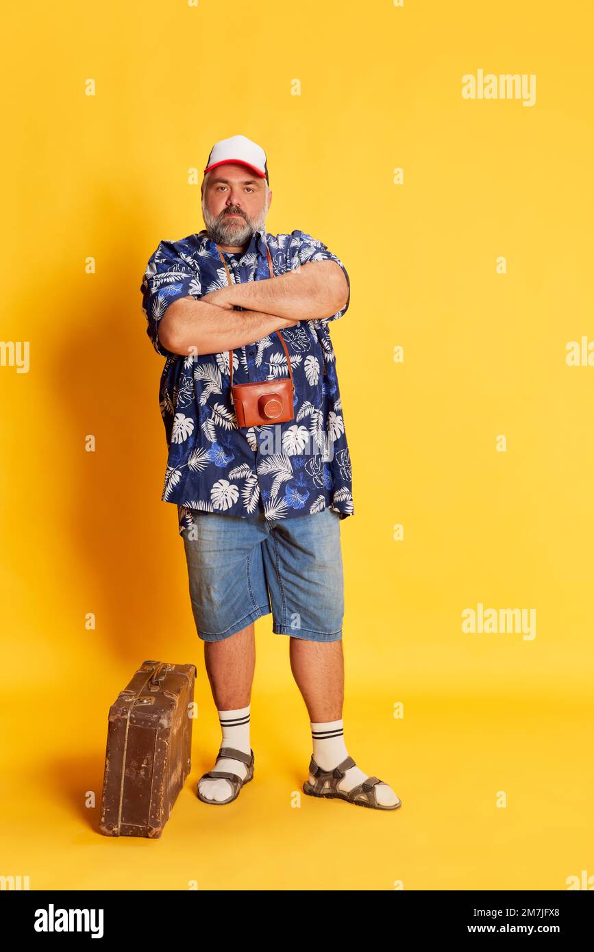 Portrait Of Fat Mature Man In Stylish Shirt Posing With Vintage Camera And Suitcase Over Bright