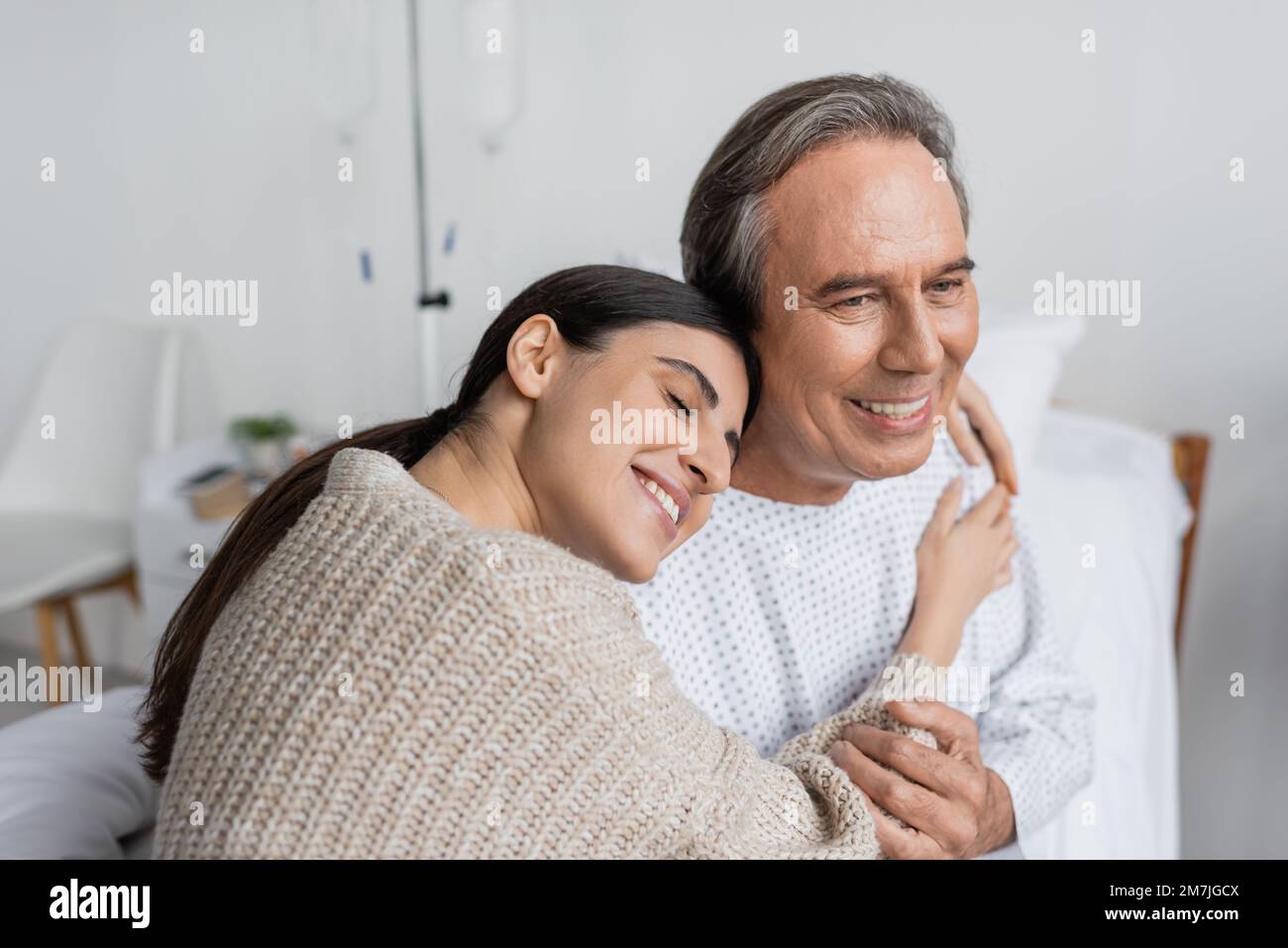 Smiling woman hugging father in patient gown in hospital,stock image ...