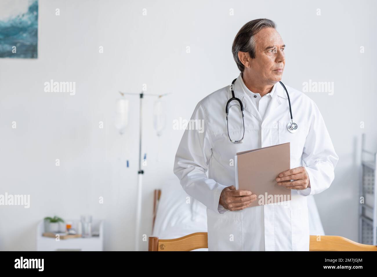 Elderly doctor holding paper folder in hospital ward,stock image Stock ...