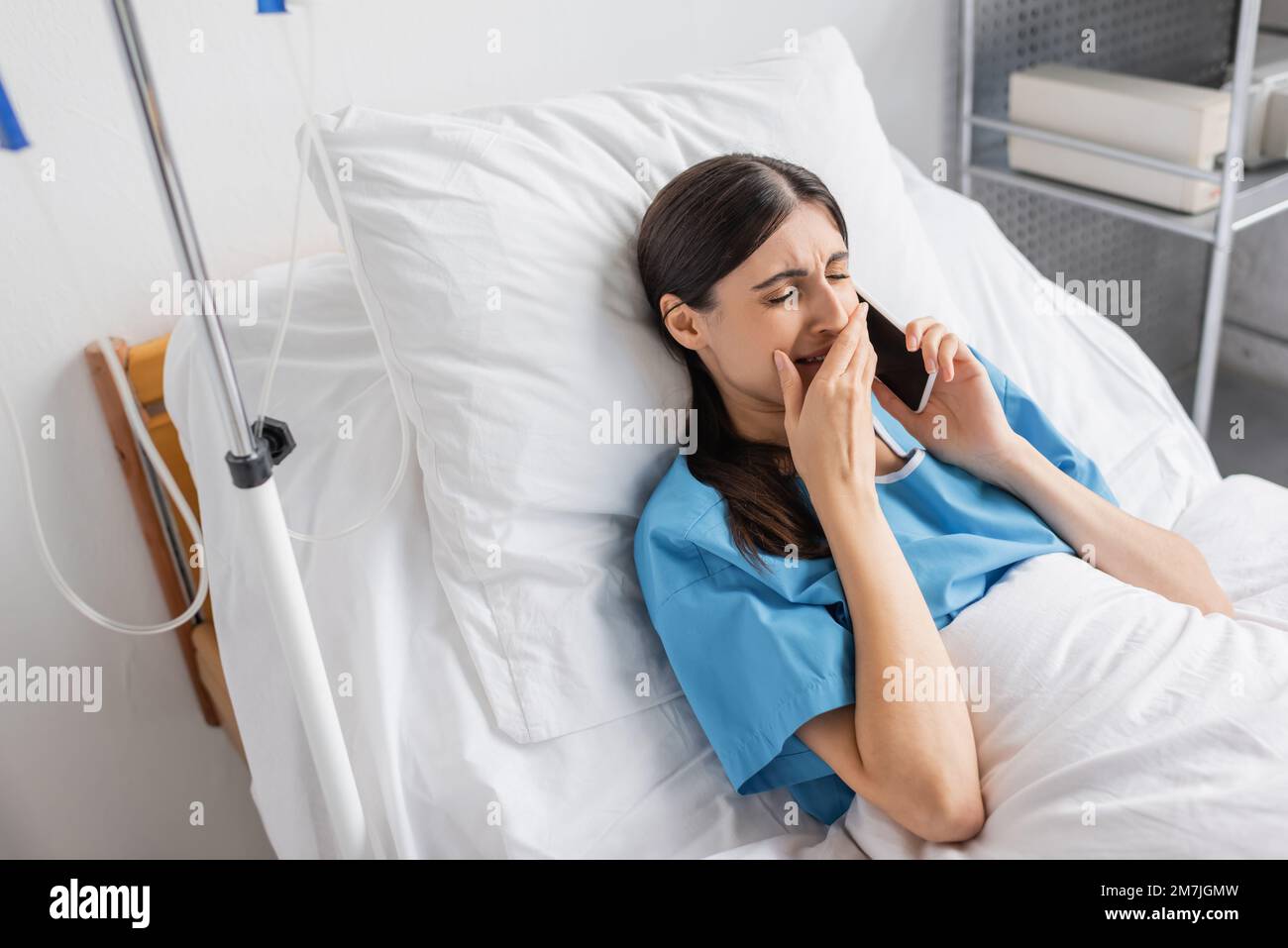 High angle view of displeased patient crying while talking on ...