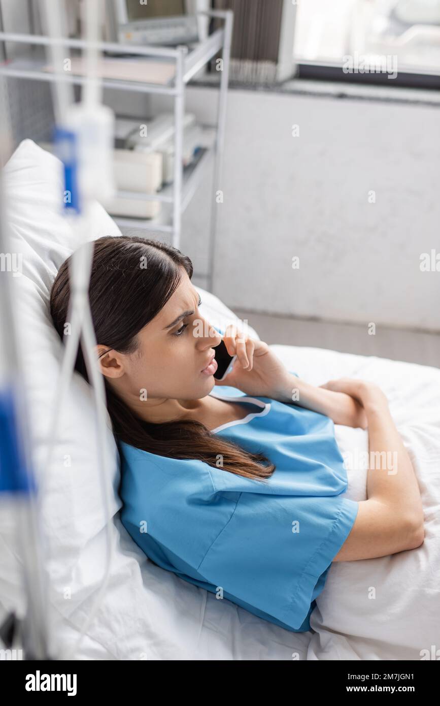 patient talking on smartphone while lying on bed near blurred ...