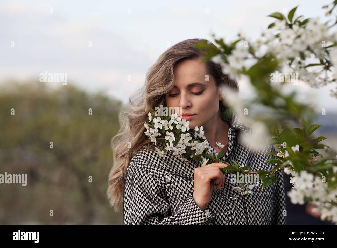 Beautiful woman smell flowers cherry tree. Female model in blooming ...