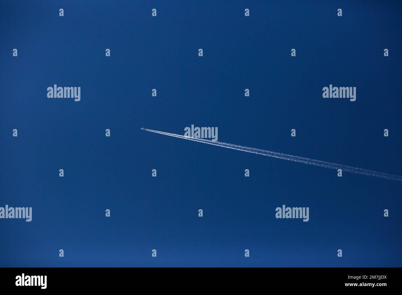 White Trails behind Airplane against Clear Blue Sky. White Jet Lines in ...