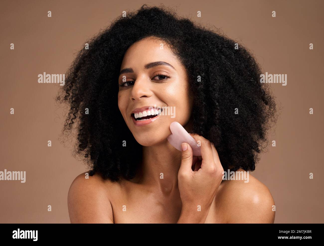 Face portrait, skincare and black woman with gua sha in studio isolated ...