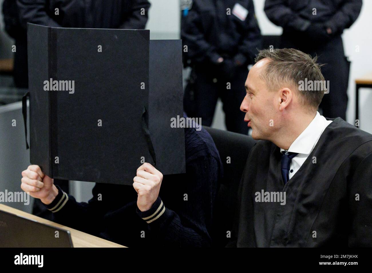 10 January 2023, Saxony, Dresden: A defendant (l) covers his face with ...