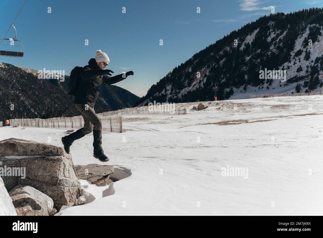 Adult male model hiking in mountains full of snow in a sunny day. He is ...