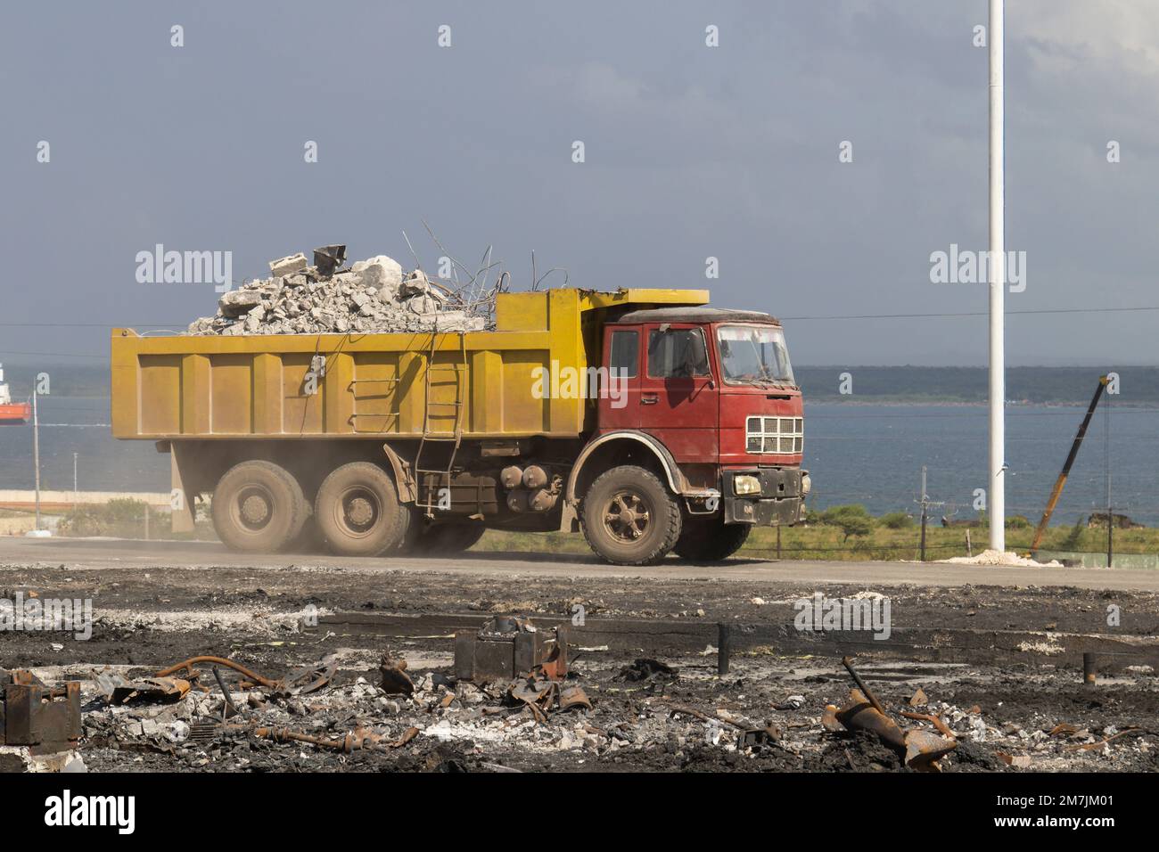 A closeup of a loaded truck transporting rubble near a damaged area ...