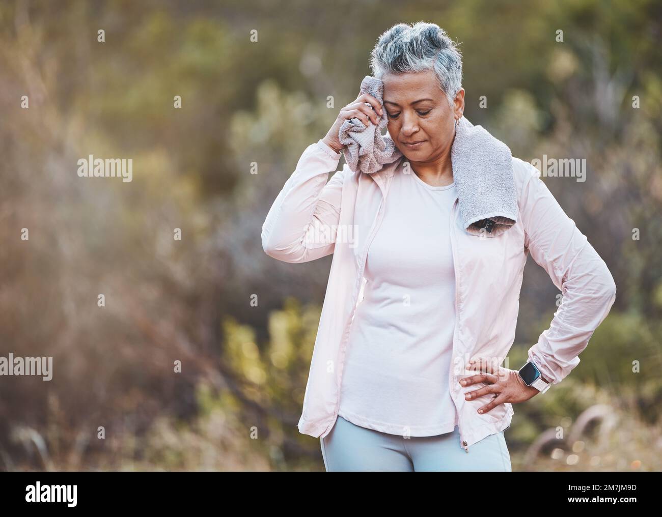Senior woman, tired and towel for sweating at park after training or ...