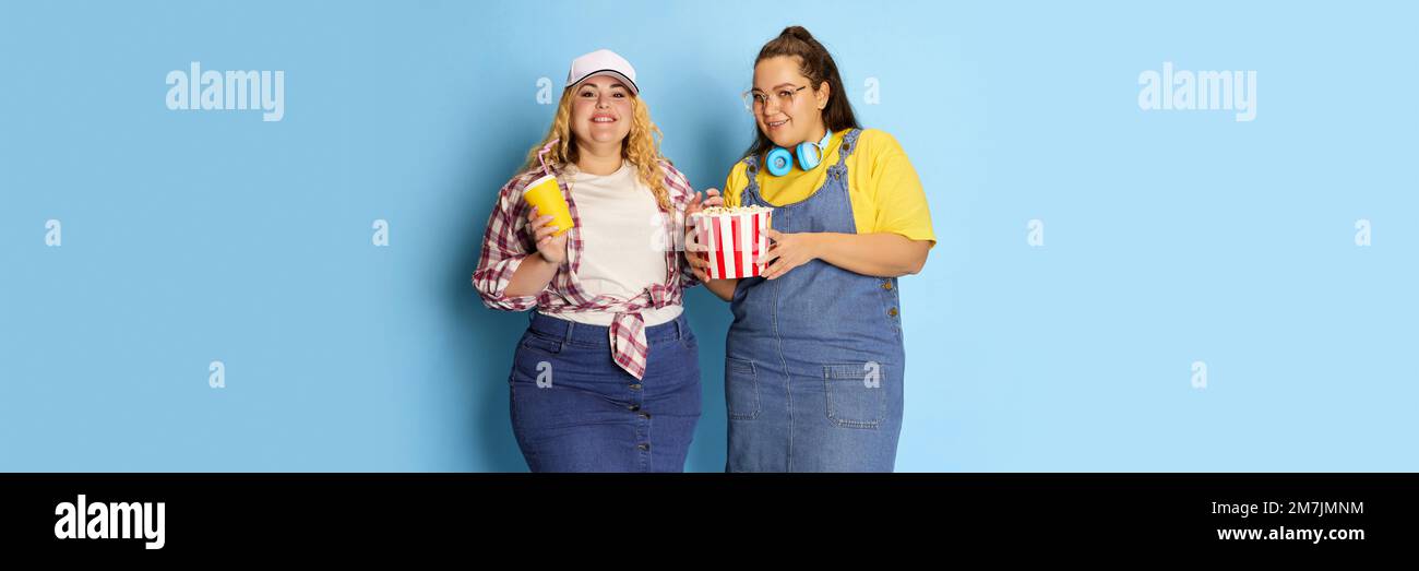 Portrait of two fat, beautiful women, friends posing with popcorn ...