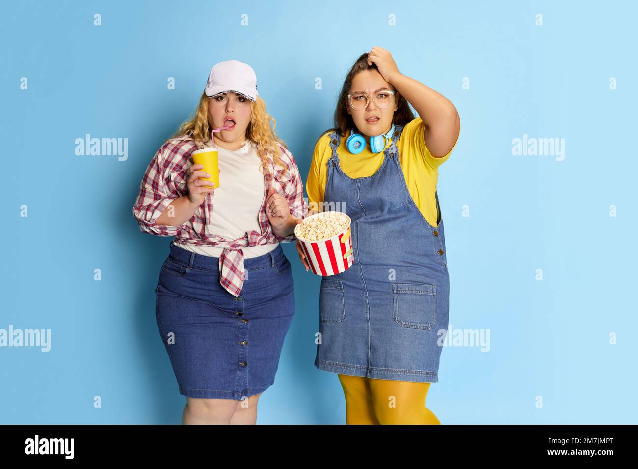 Portrait of two fat, beautiful women, friends posing with popcorn ...