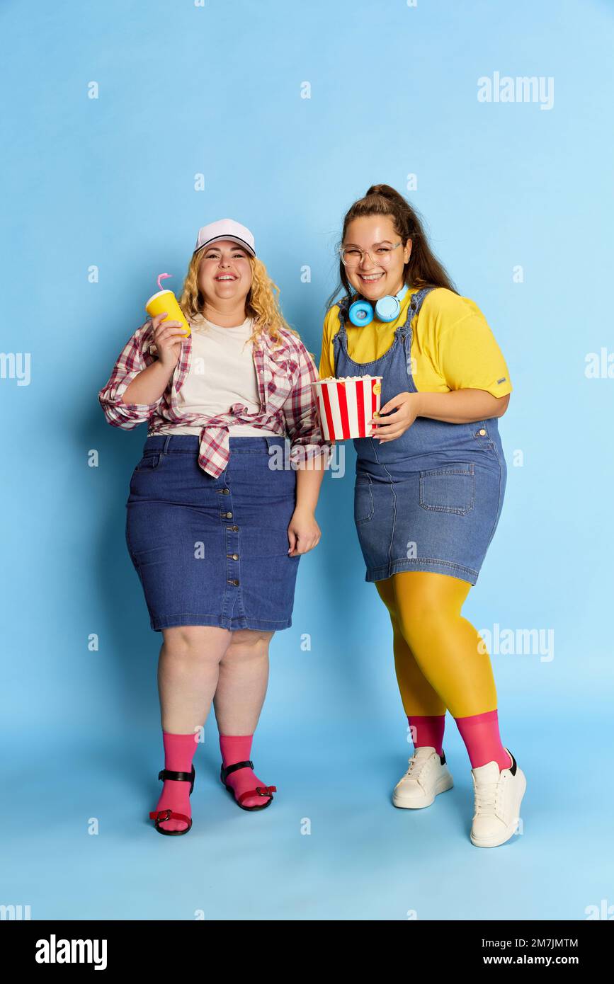 Portrait of two fat, beautiful women, friends posing with popcorn ...