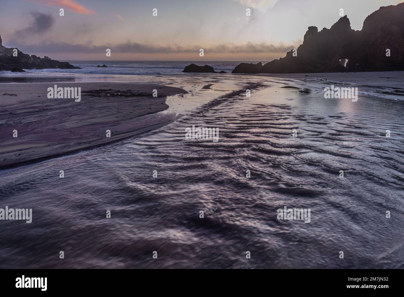 Close-up of a small stream of water flowing into the pacific ocean at ...