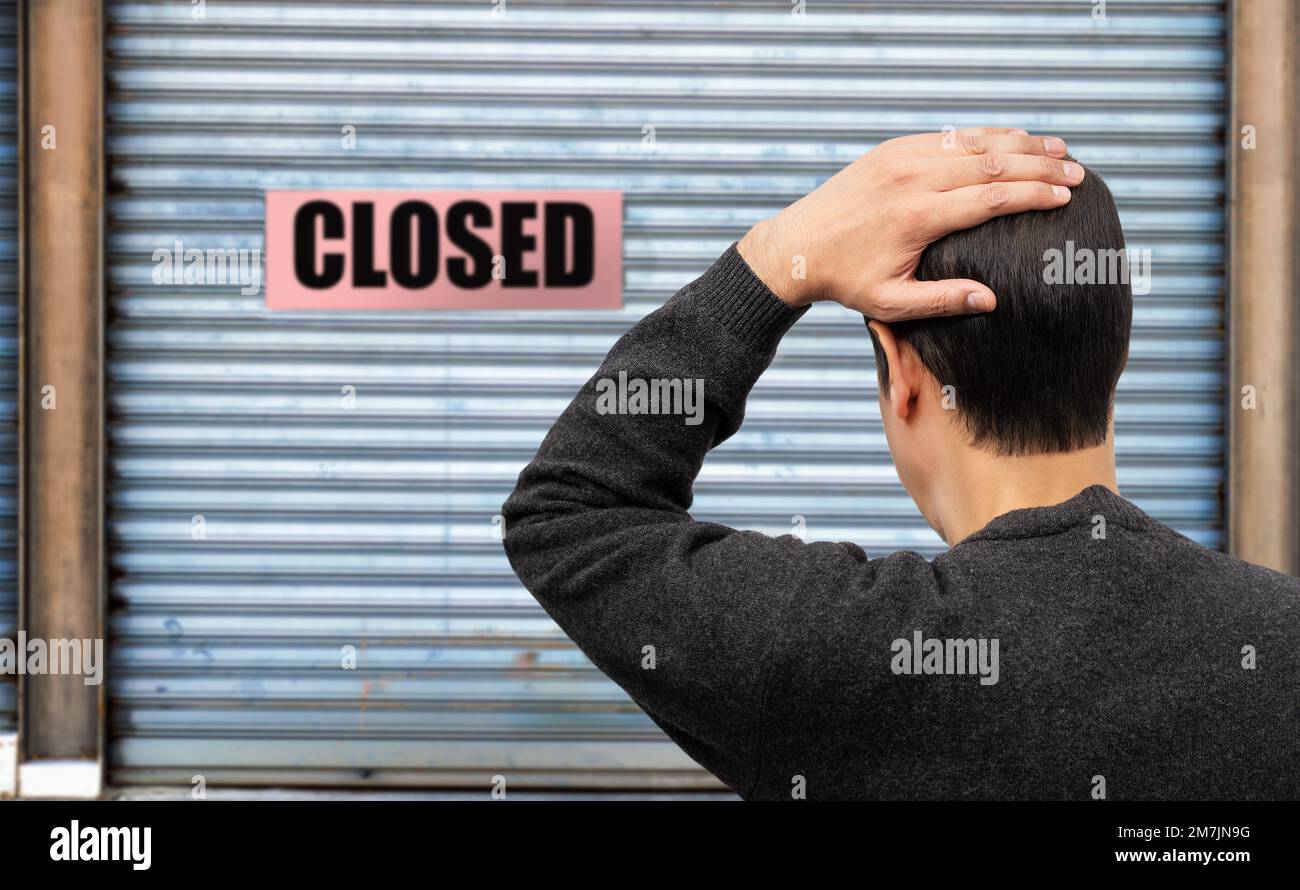 Rear view of a confused young man looking at business office or store ...