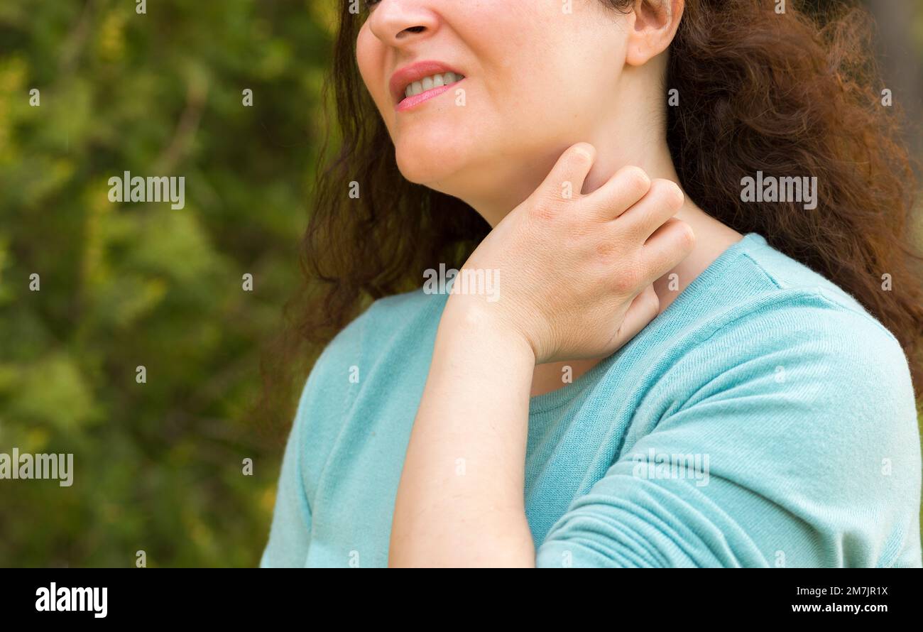 Close-up of woman suffering itching scratching neck standing outdoors ...