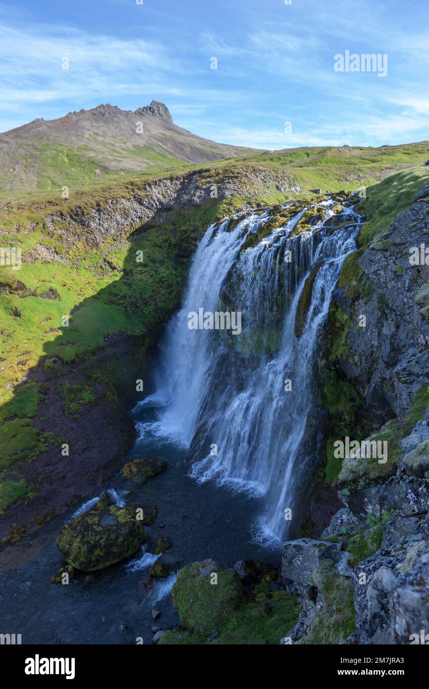 Iceland landscape with high waterfall among green hills. Beautiful ...
