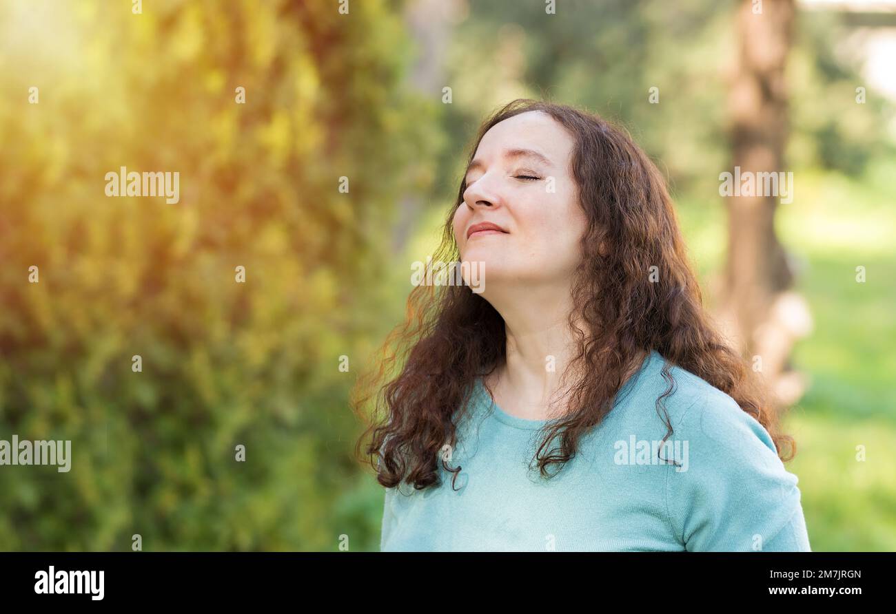 Woman breathing fresh air in a green forest in summer wearing a blue ...