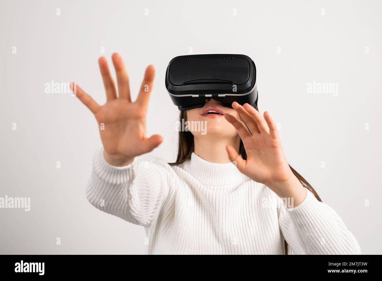 Woman enjoys virtual reality looking through VR goggles at home. Young ...