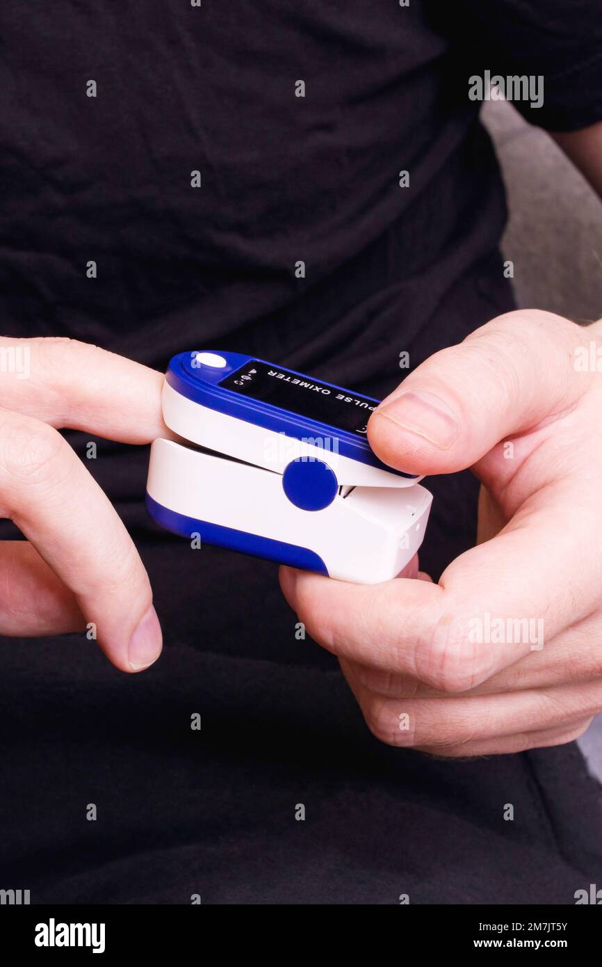 Hand puts pulse oximeter on middle finger Stock Photo - Alamy