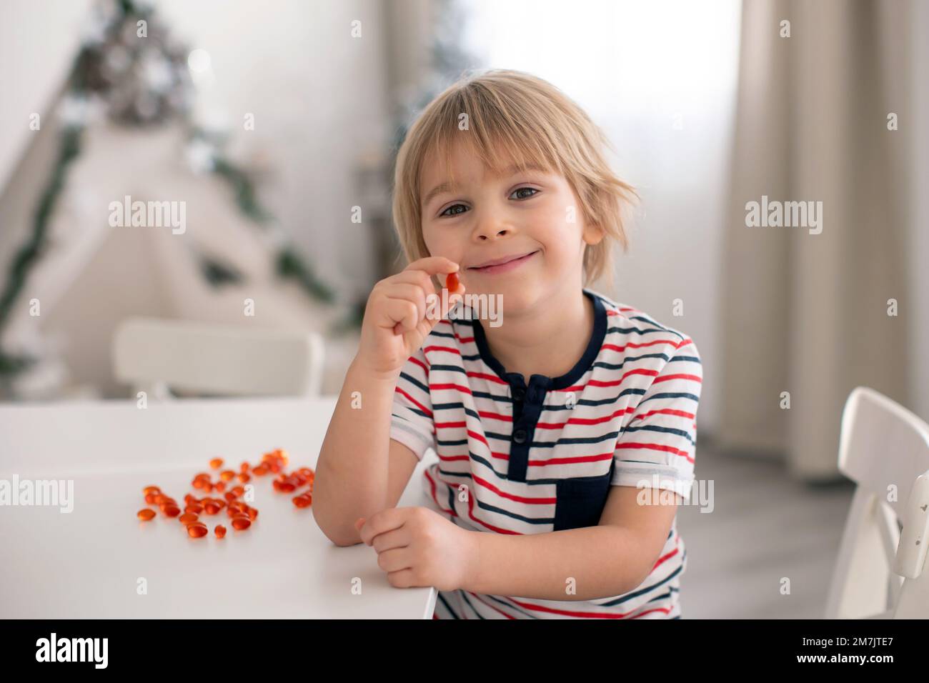 Cute little child, toddler boy, eating alfa omega 3 child suplement ...