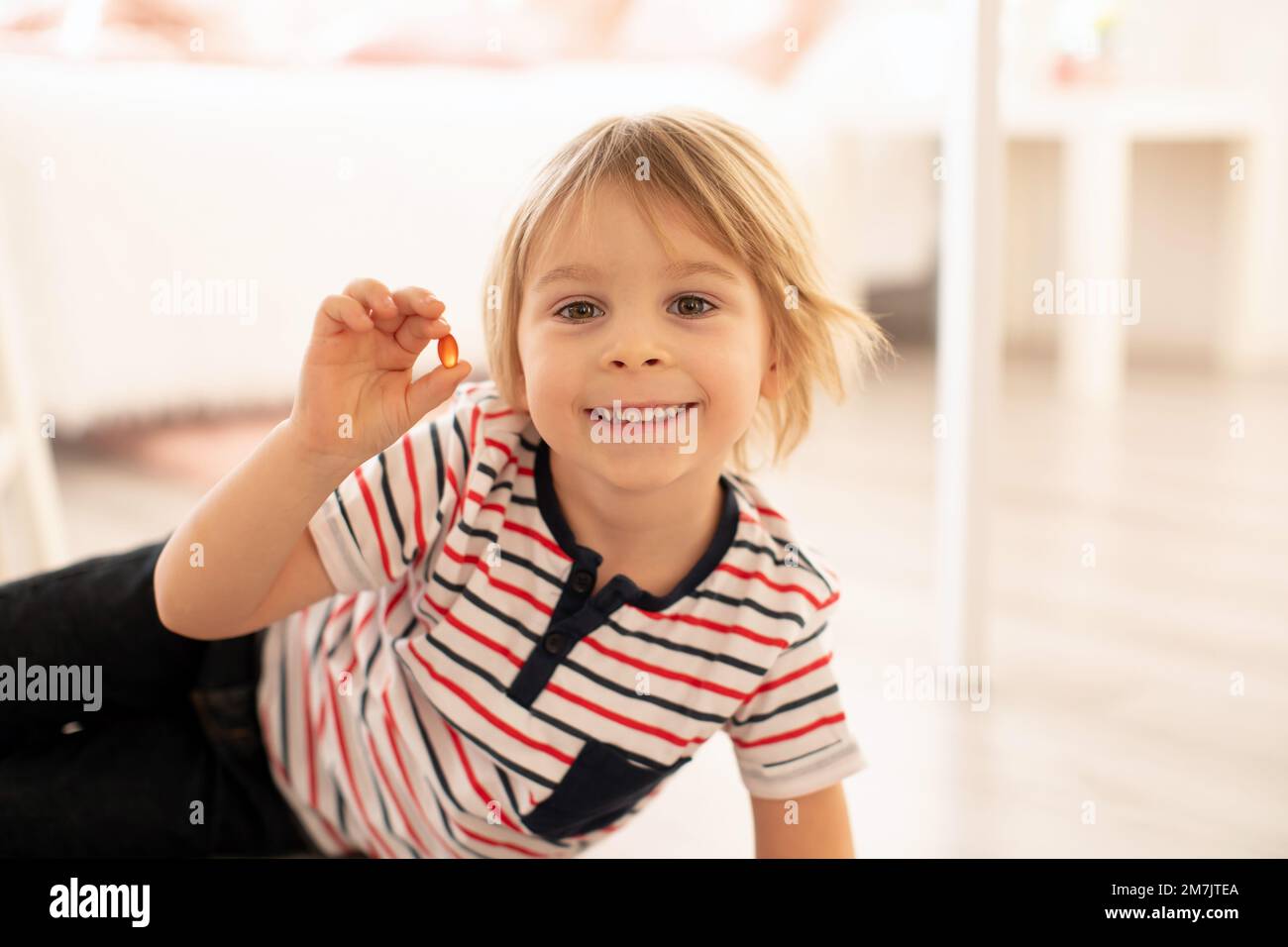 Cute little child, toddler boy, eating alfa omega 3 child suplement ...