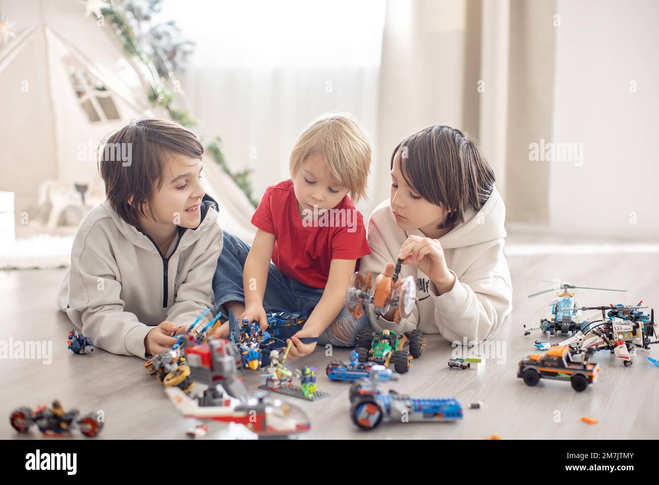 Cute toddler child and older brothers, blond boy, playing with colofrul ...