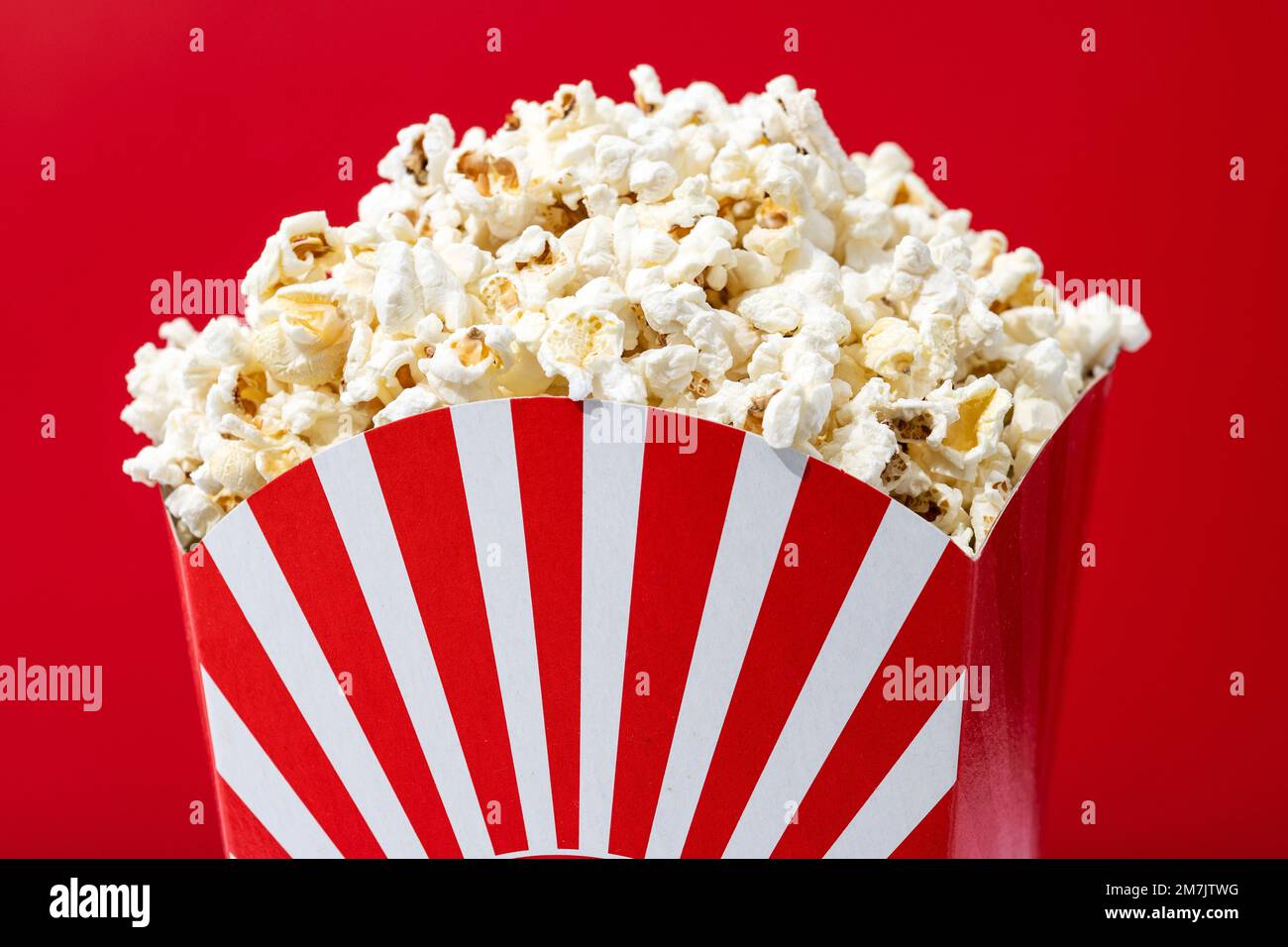 Salted popcorn in carton package on white marble and red background ...