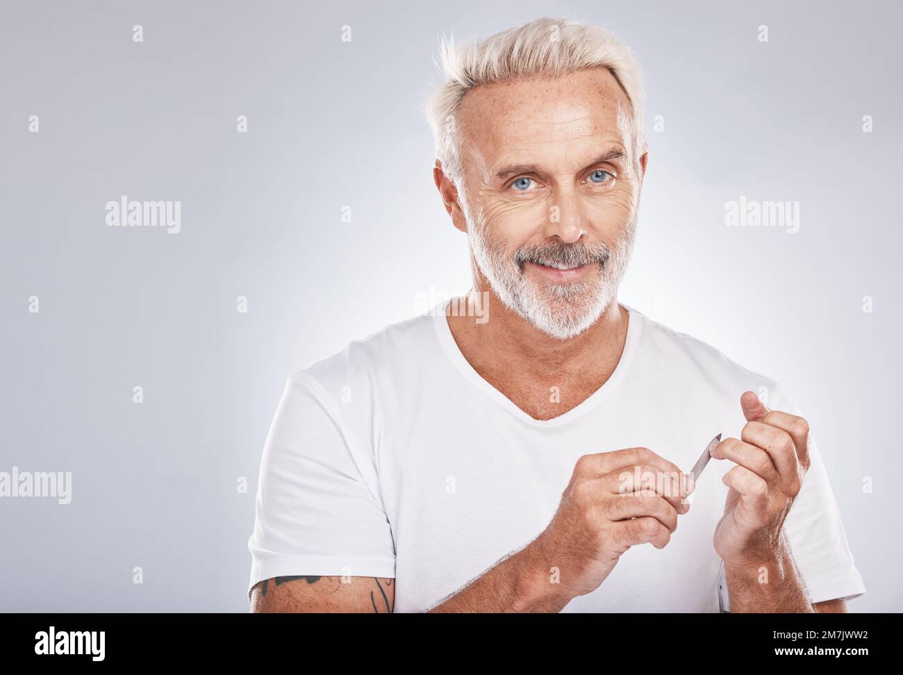 Portrait, nail file and grooming with a man in studio on gray ...