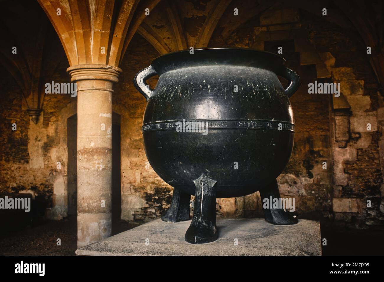 A big black cast iron metal cauldron in a medieval castle basement ...