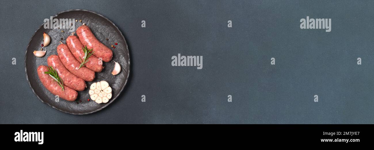 Long banner with raw sausages or bratwurst with seasonings on black ...