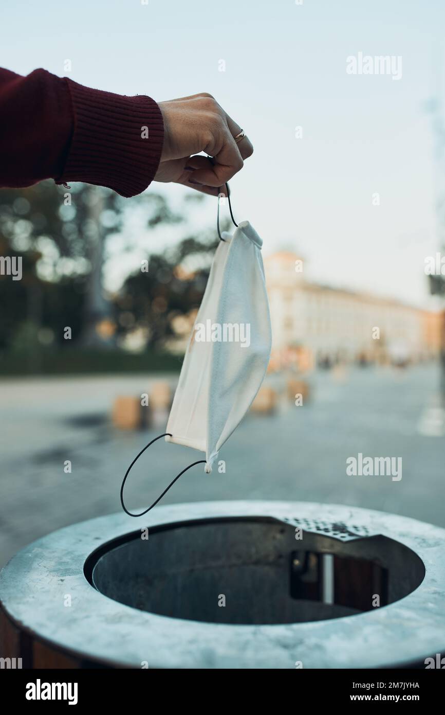 Woman female hand throwing out used face mask to trash Stock Photo - Alamy
