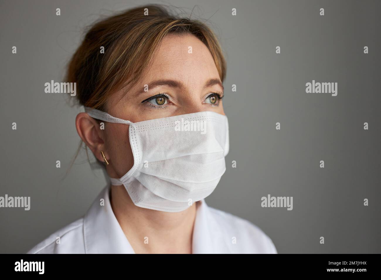 Doctor with face covered with mask. Portrait of young woman wearing the ...