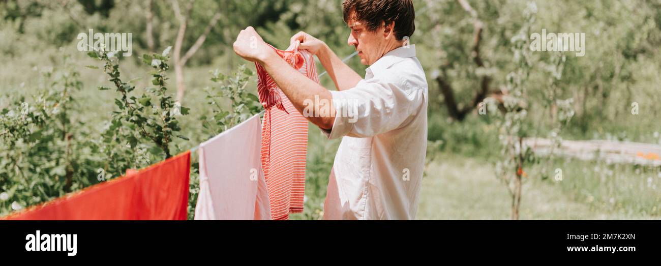 candid young mature choring man chore homework and hanging the laundry ...