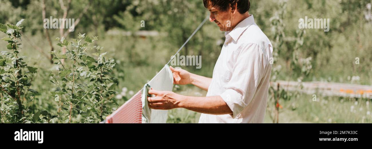 candid young mature choring man chore homework and hanging the laundry ...